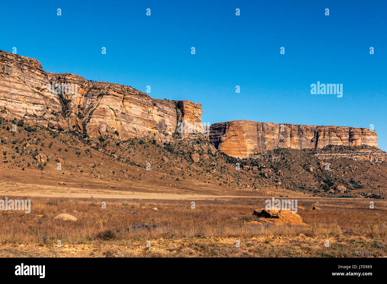 Golden cold dry winter landscape and rocky mountain against blue cloudy ...