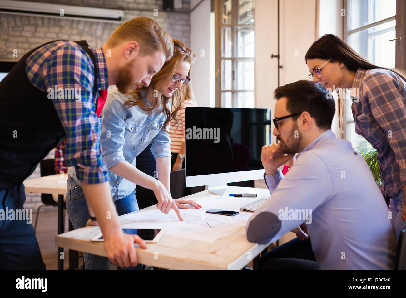 Coworkers working on project together in office Stock Photo - Alamy