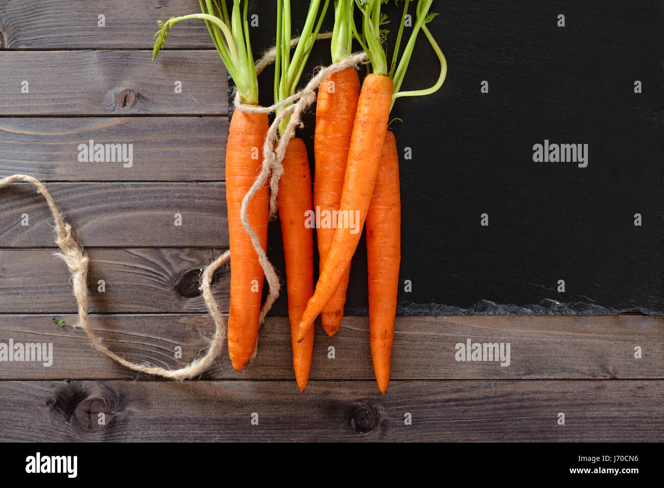 Heap of ripe carrots with leaves on dark slate Stock Photo - Alamy