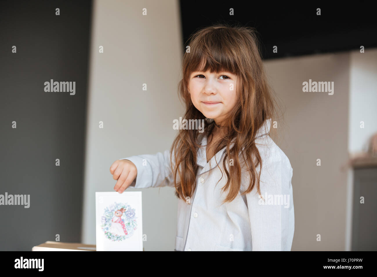 Little girl showing cute postcard in living room Stock Photo - Alamy