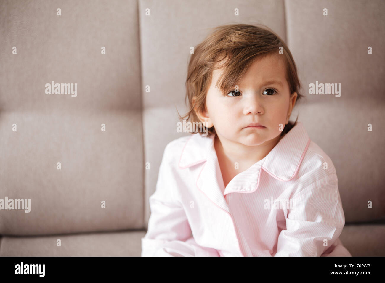 Upset child sitting on sofa and looking away Stock Photo - Alamy
