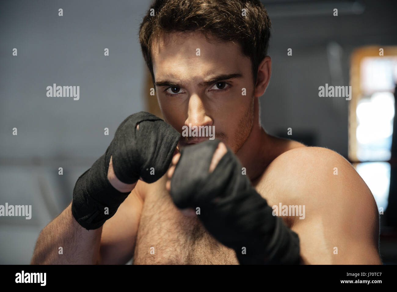 Portrait of young man boxer looking camera with rewounded hands in the ...