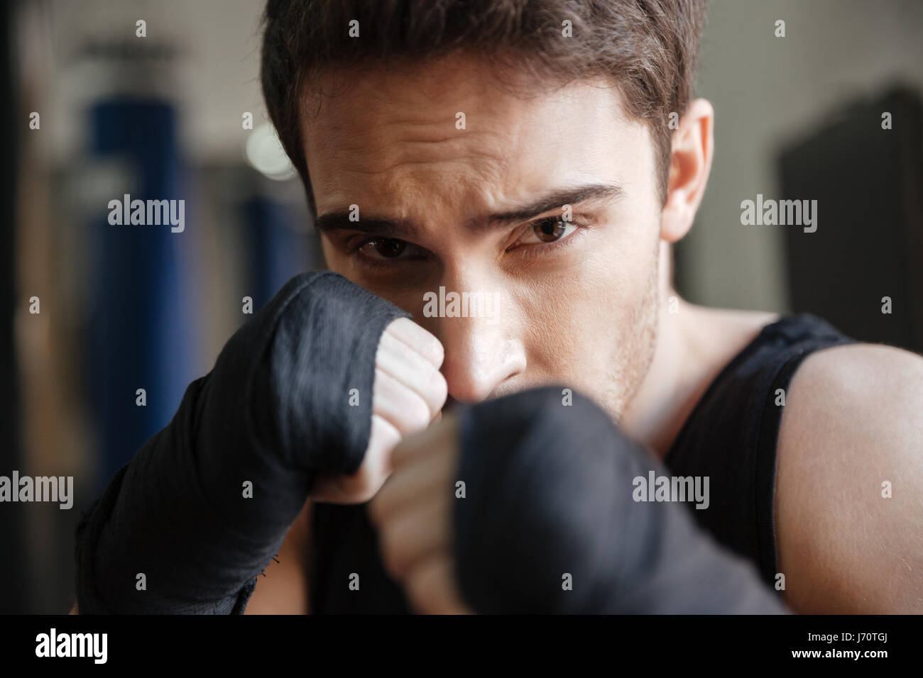 Close up view of a serious boxer doing exercise in gym and looking at ...