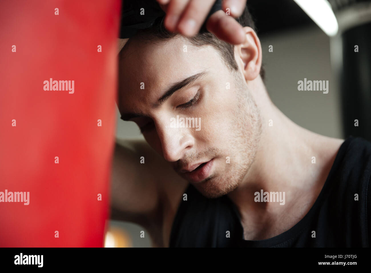 Portrait of tired boxer looking down near punching bag Stock Photo - Alamy