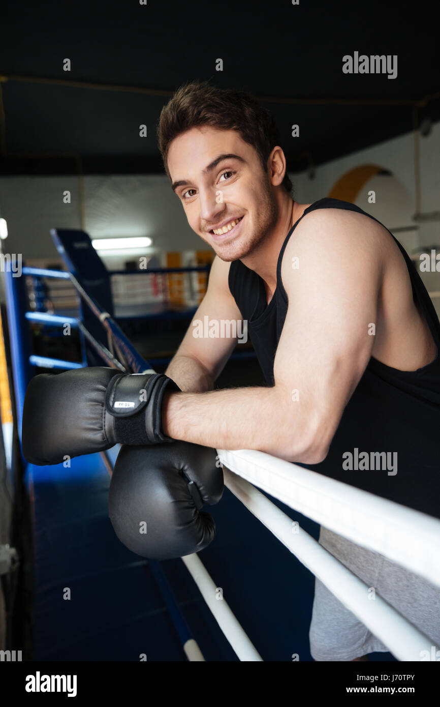 Smiling boxer in black boxing gloves looking at camera in gym Stock ...