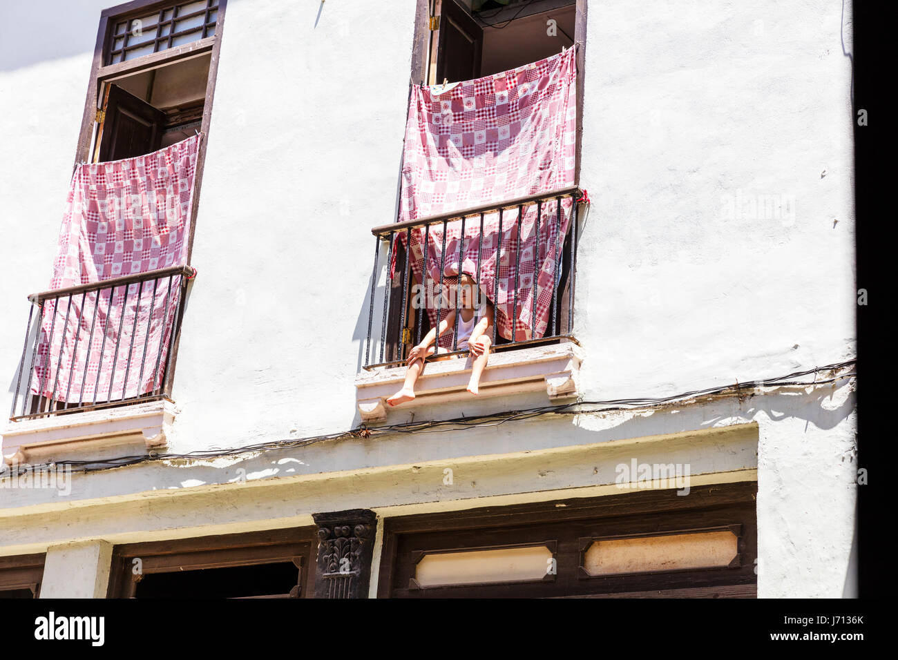 Young boy on hotel balcony alone, young boy looking through railing on ...
