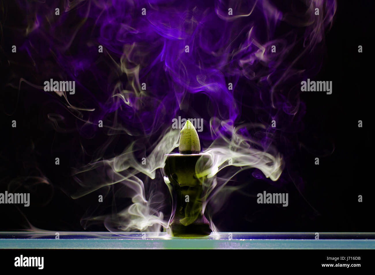 Aromatic cone smoldering in a ceramic stand and emits smoke of ...