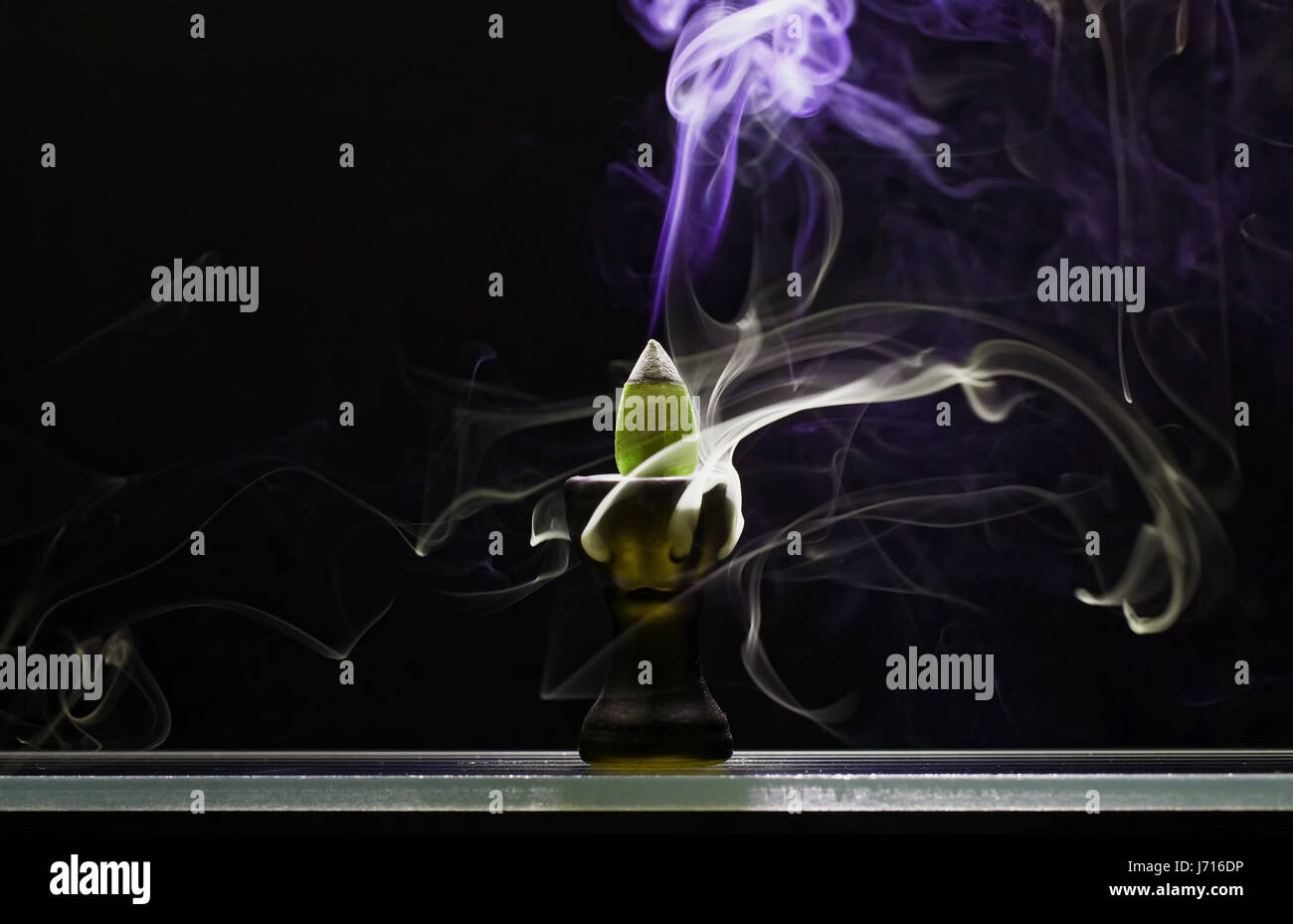 Aromatic cone smoldering in a ceramic stand and emits smoke of ...