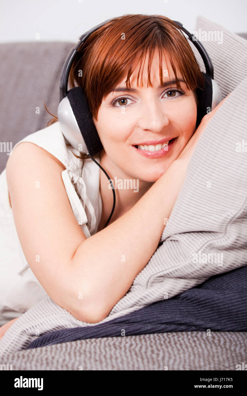 woman listen music earphones headphones seated home humans human beings ...