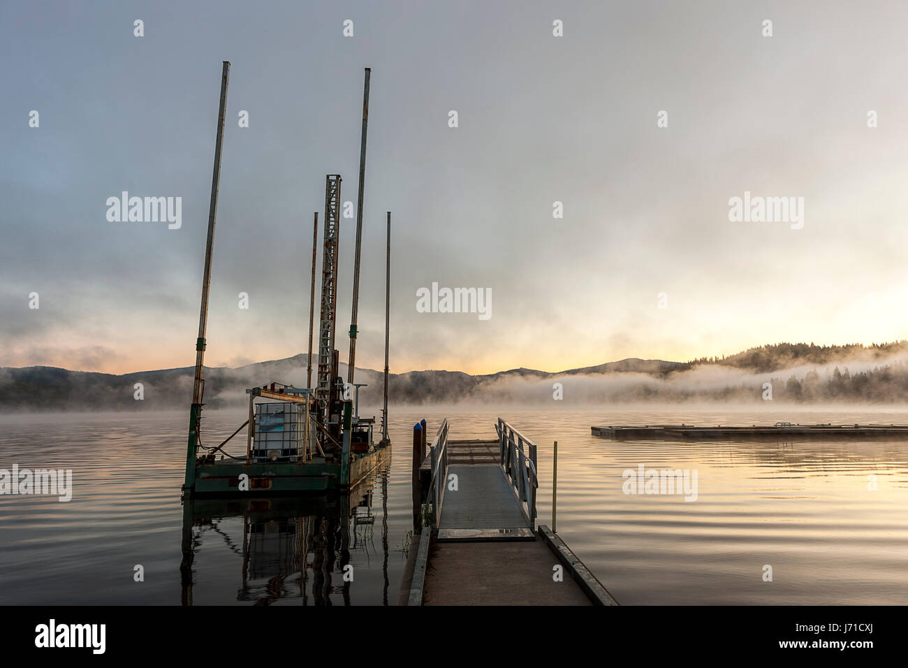 A small barge by a dock at sunrise in Hauser Lake, Idaho Stock Photo ...
