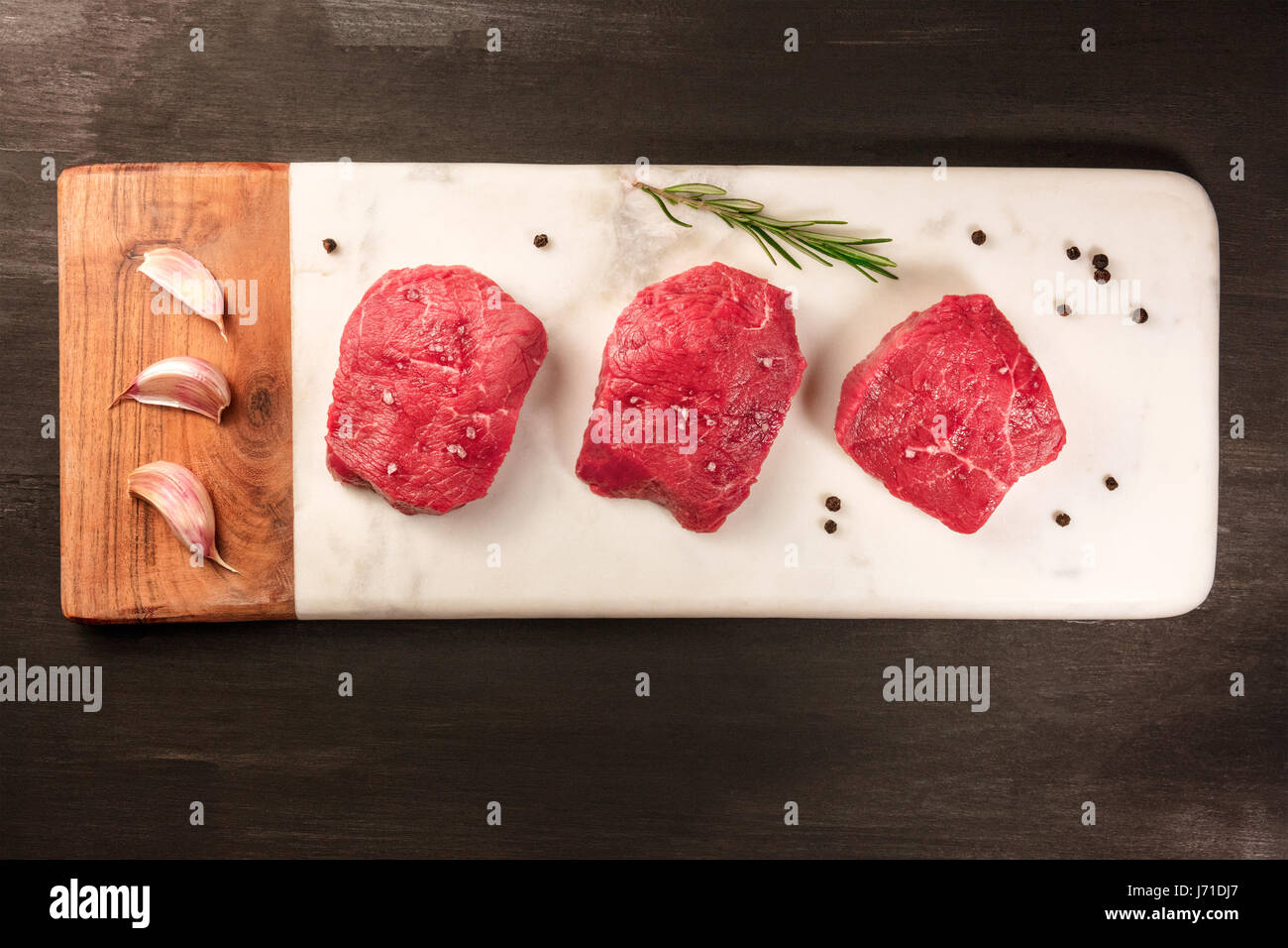 Three slices of raw meat, beef fillet, shot from above on with a sprig ...