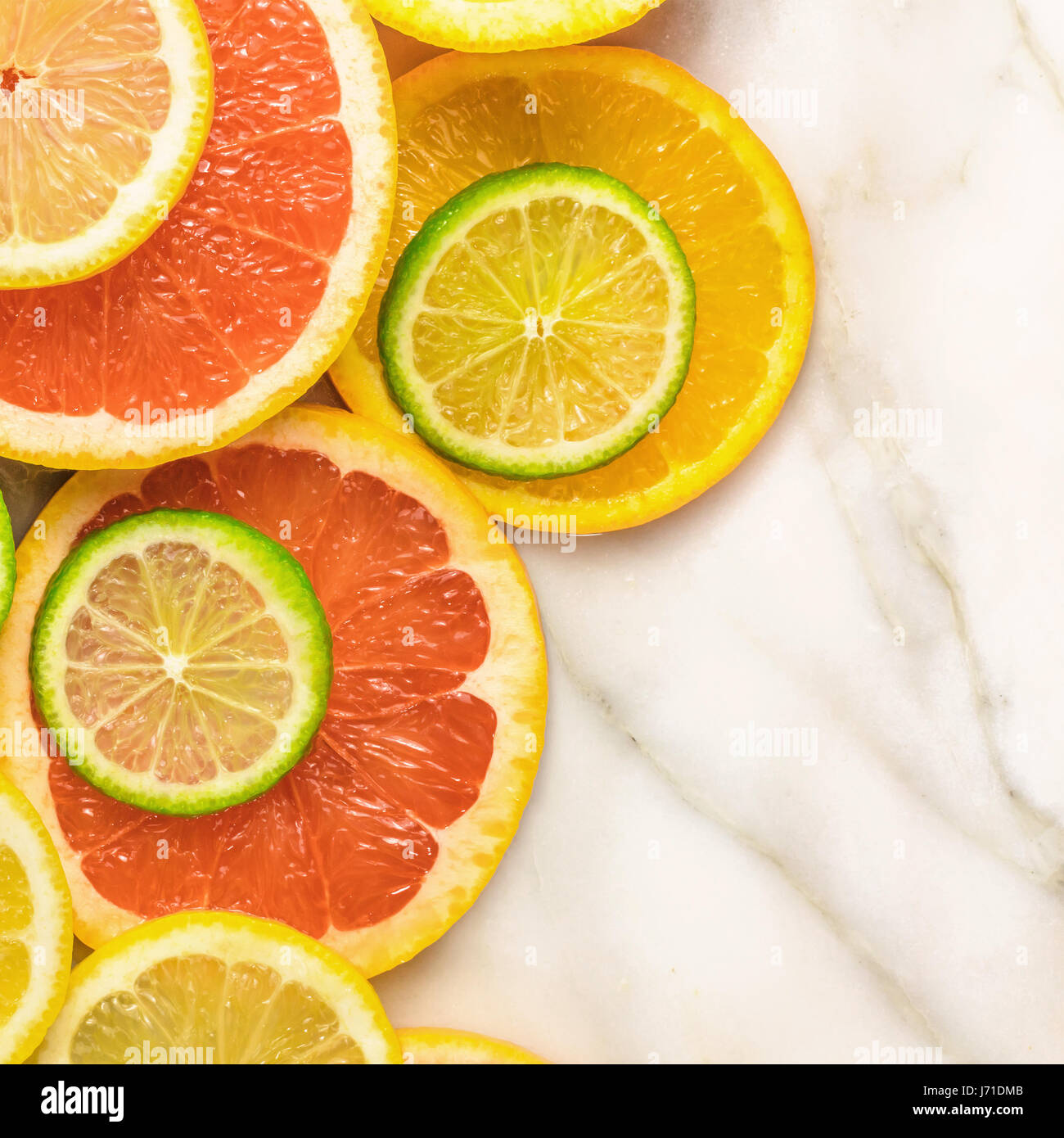A square photo of vibrant juicy citrus fruits on a white marble texture ...