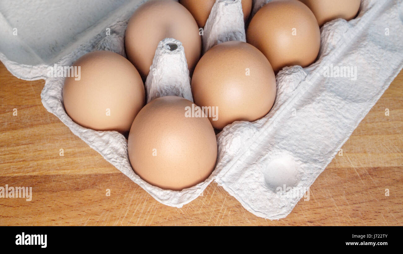 Packing eggs in a cardboard box from above and close-up on a wooden ...