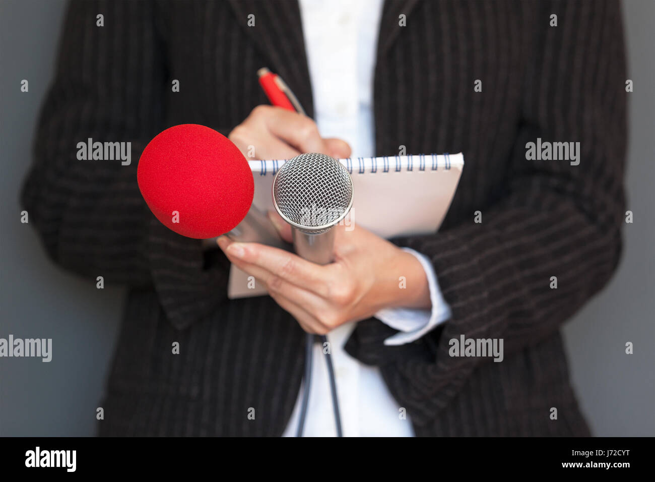 Female reporter at news conference, writing notes, holding microphones ...