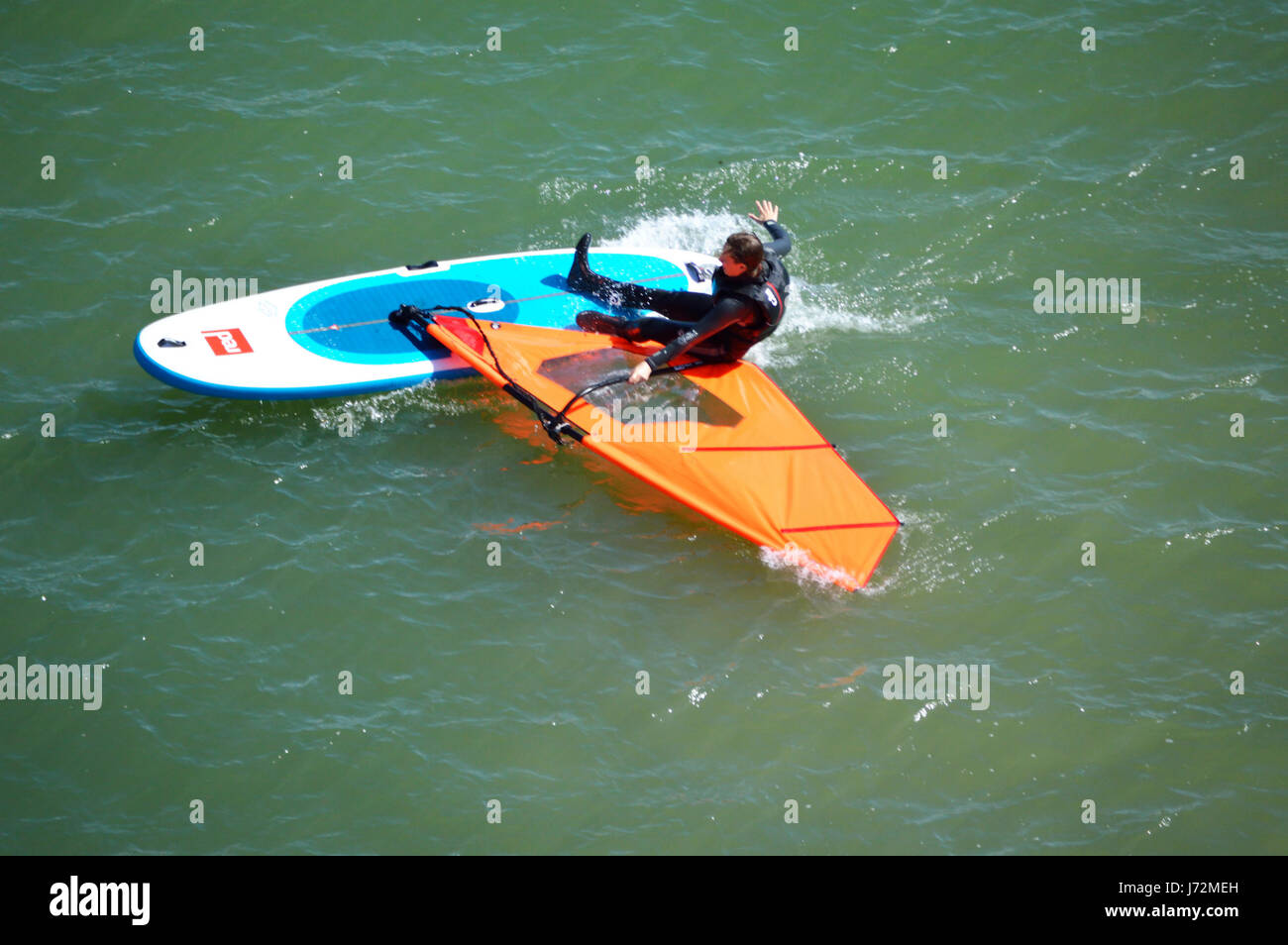 Girl falling off surfboard whilst learning to windsurf, UK Stock Photo ...