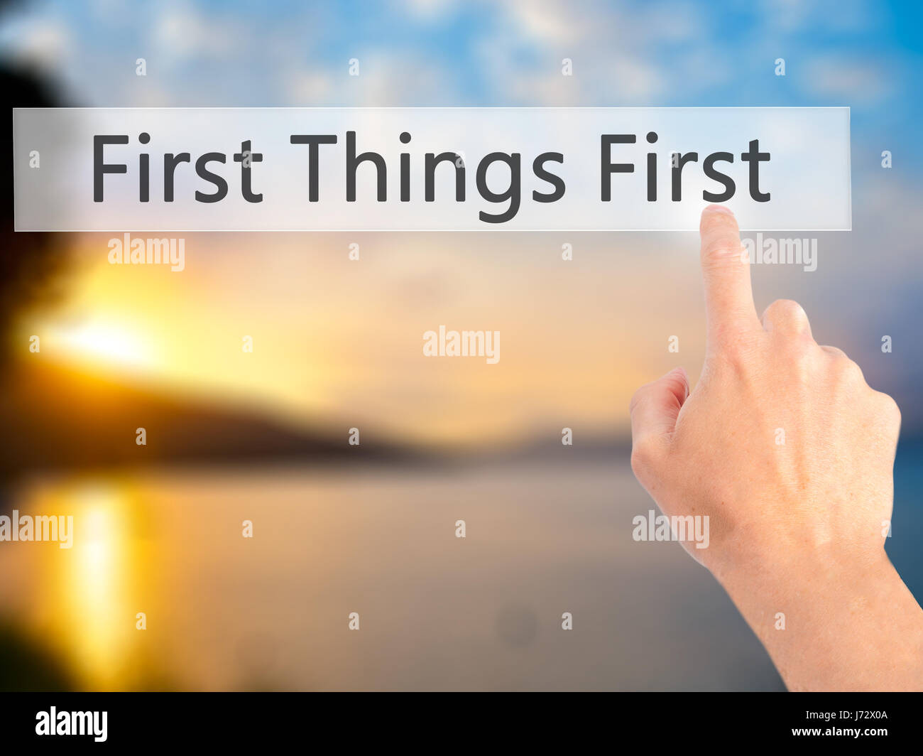 First Things First - Hand pressing a button on blurred background ...