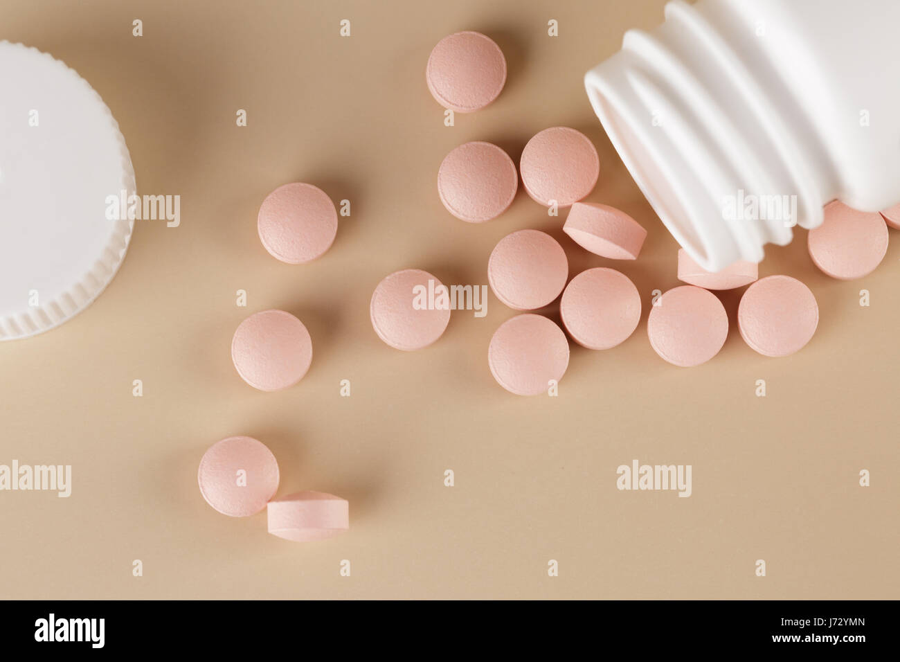 Round brown pills and white plastic bottle on beige background Stock ...