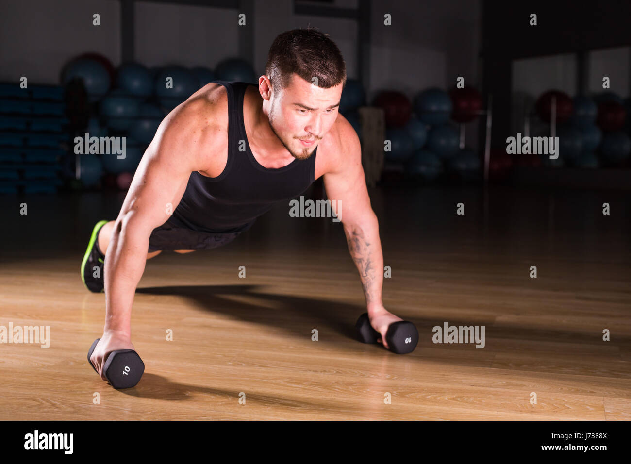 Young Man Athlete Doing Pushups With Dumbbells As Part Of Bodybuilding ...