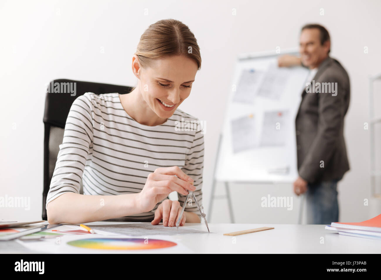 Cheerful female engineer drawing with compasses Stock Photo - Alamy