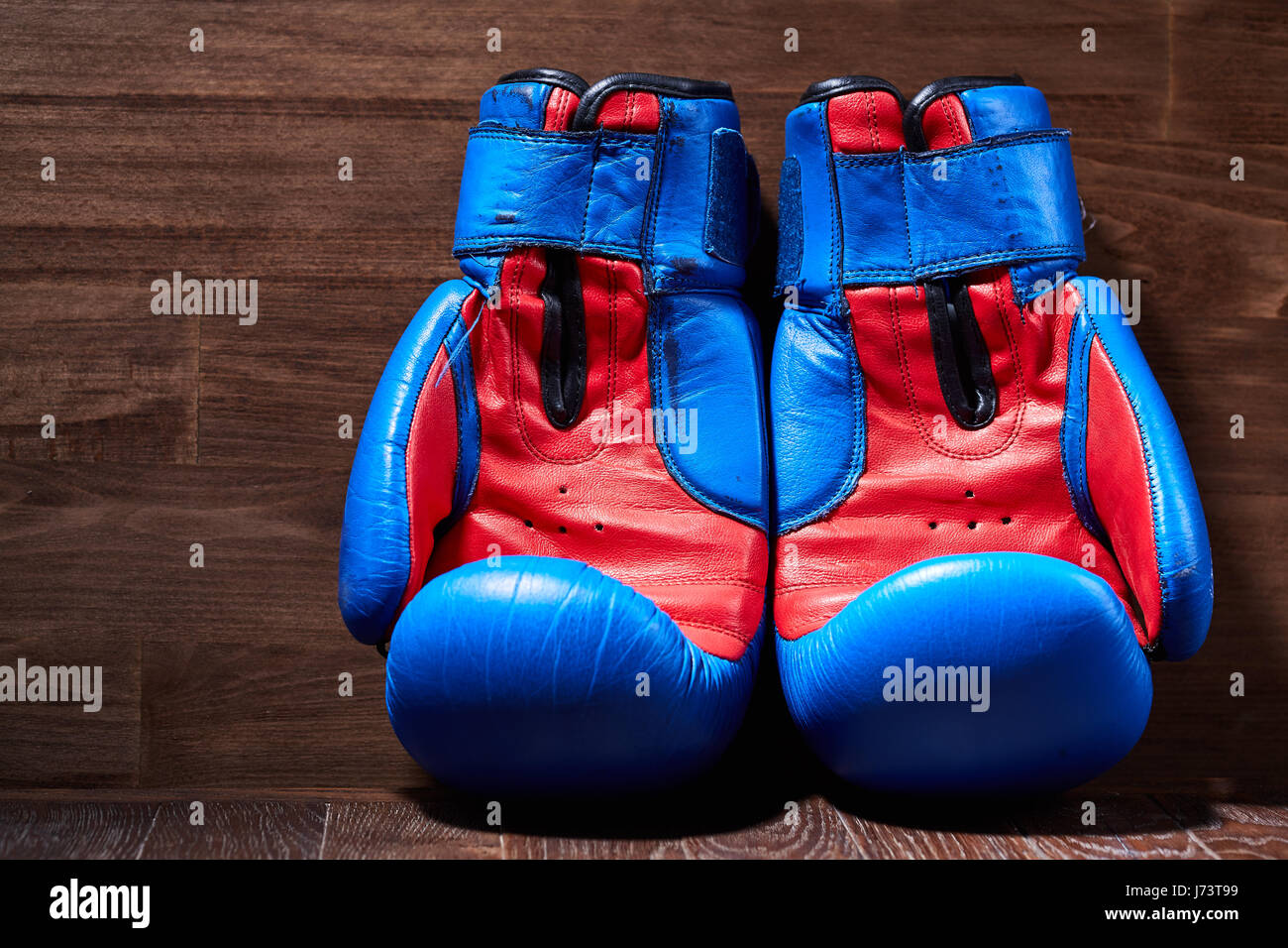 Close-up of the pair of red and blue boxing gloves on the wooden plank ...