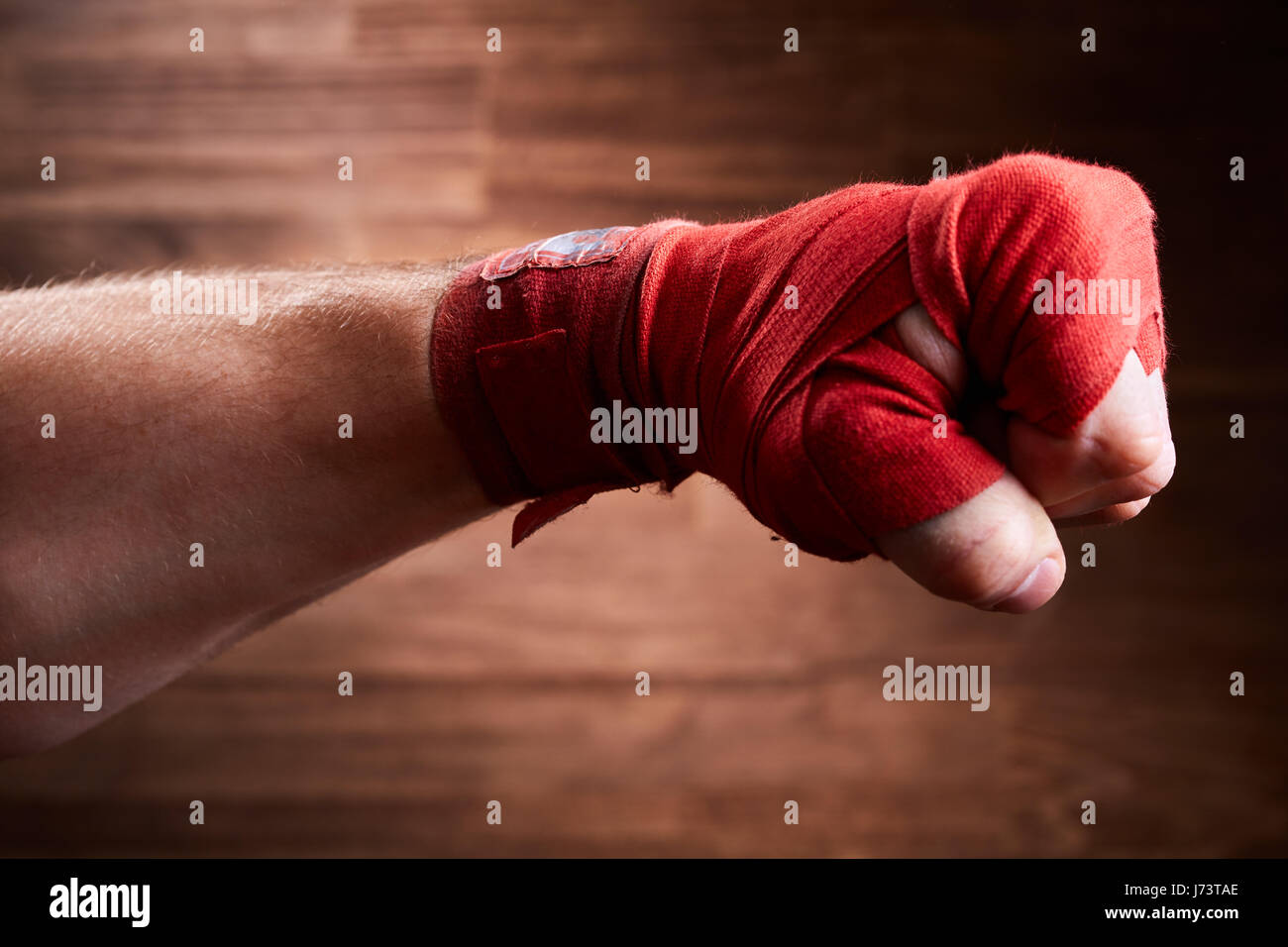 Close up image of fist of a boxer with red bandage against brown ...