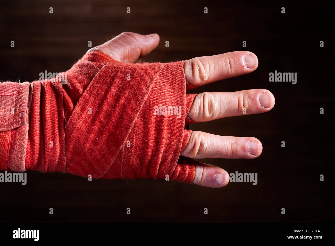 Close-up image of boxer's hand with a red bandage against brown ...