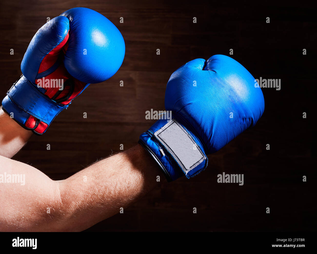 Blue and red boxing gloves on hands on brown background Stock Photo - Alamy