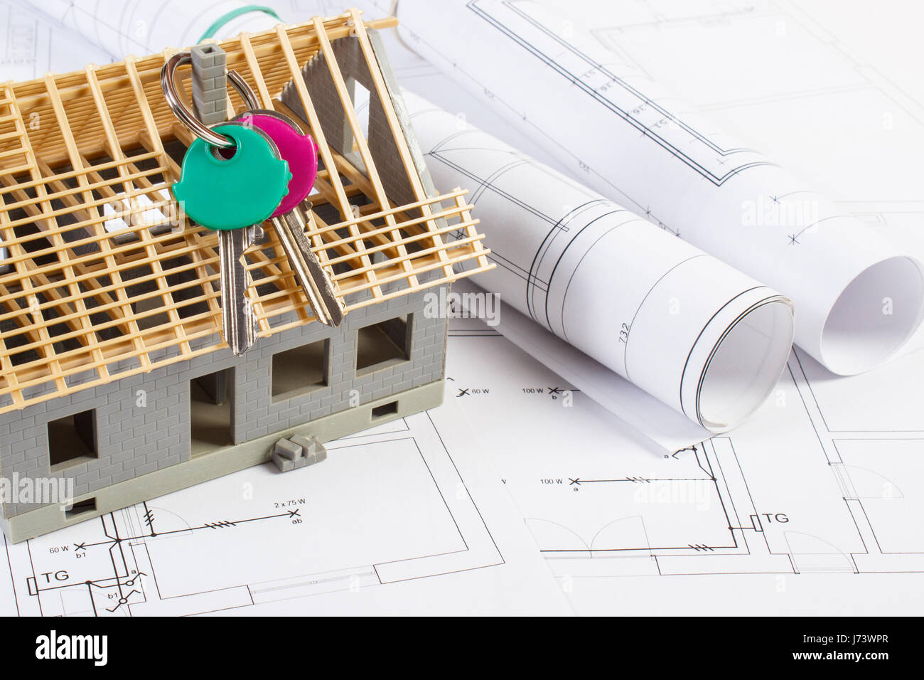Small house under construction with home keys and electrical rolls of ...