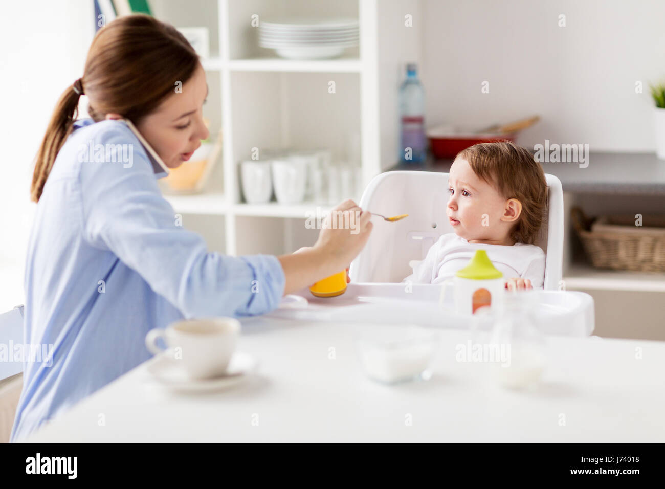 mother with smartphone feeding baby at home Stock Photo - Alamy