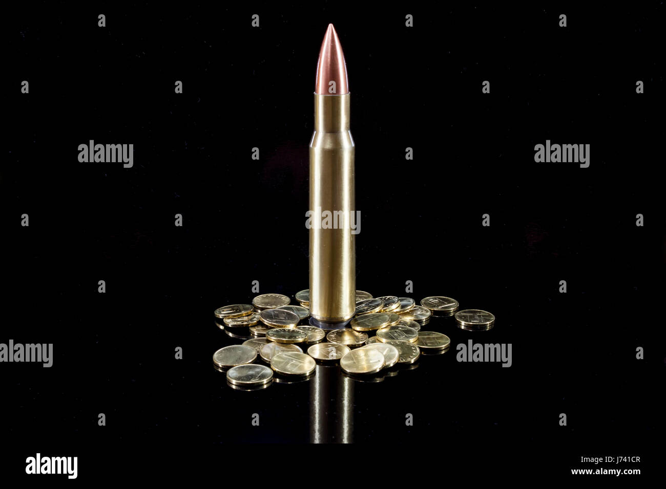 High caliber bullet vertically placed and surrounded by golden coins ...