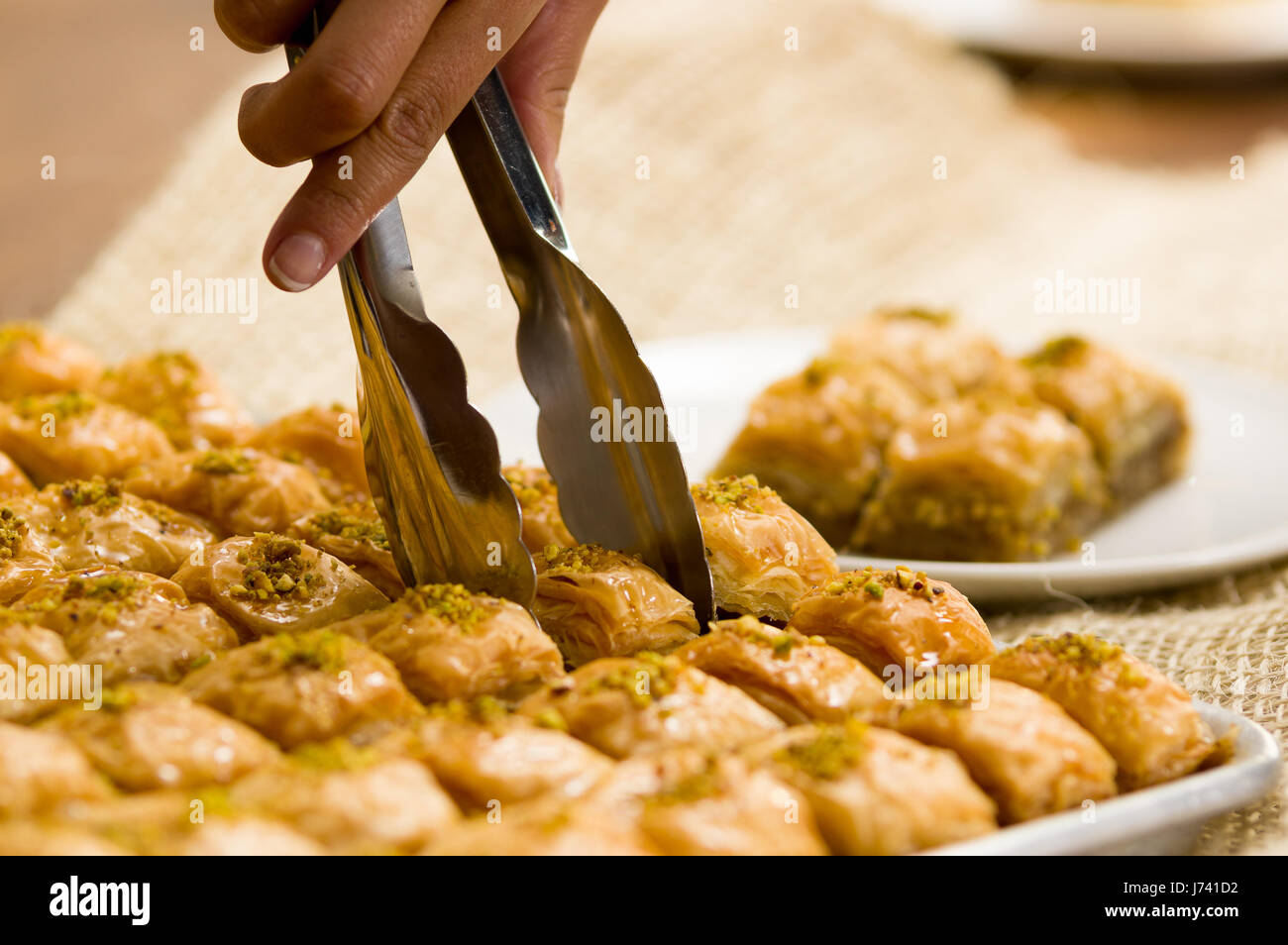 Close up of a man using a Bakery clamps to take a baklava food ...
