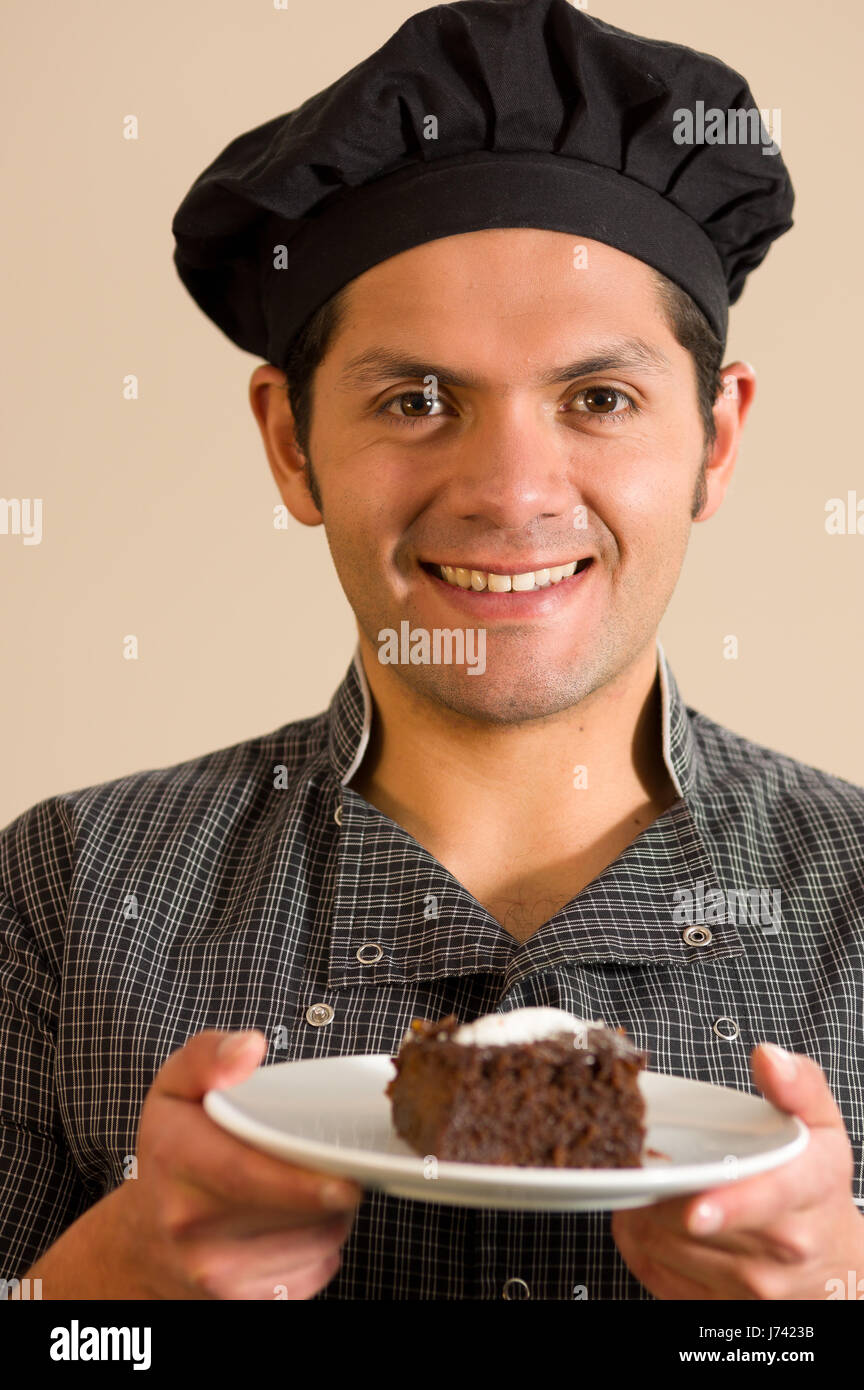 Handsome smiling man holding a piece of dark chocolate cake in a soft ...