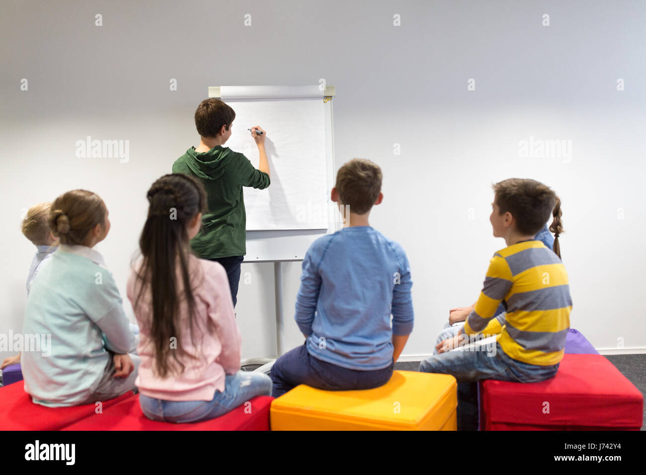 student boy with marker writing on flip board Stock Photo - Alamy