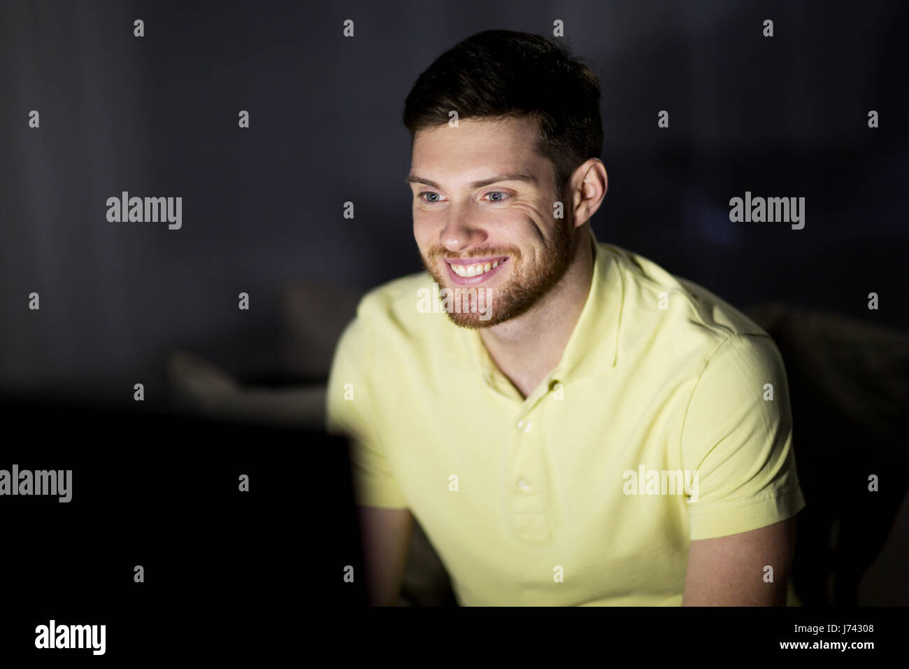 happy smiling young man watching tv at night Stock Photo - Alamy