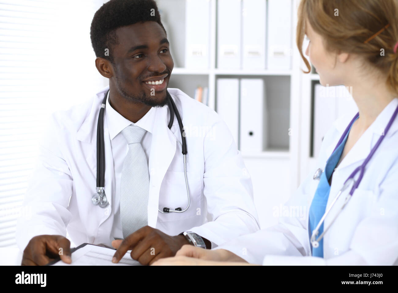 Happy smiling african american male doctor talking with colleague while ...