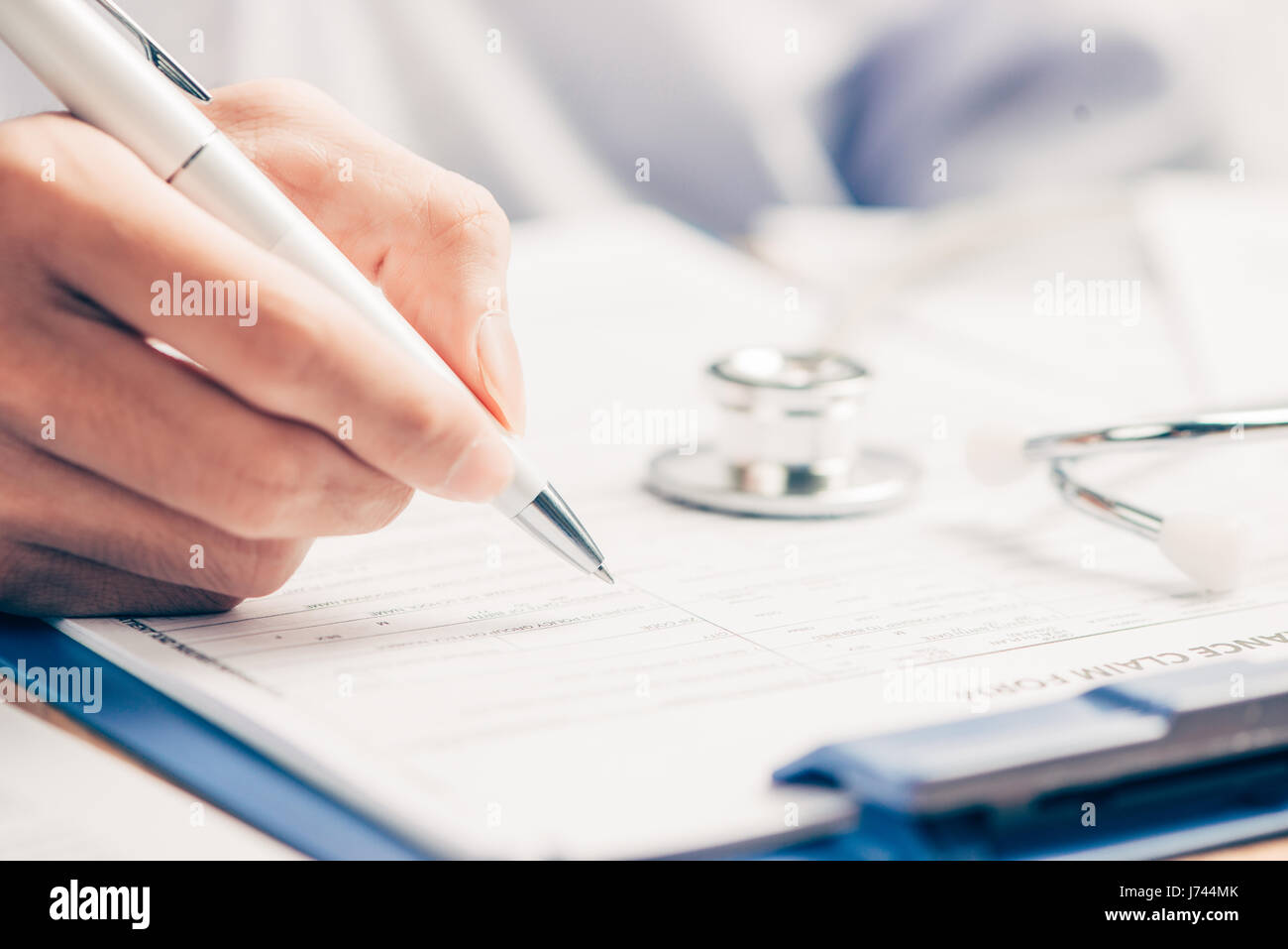 Female doctor filling medical form on clipboard Stock Photo - Alamy