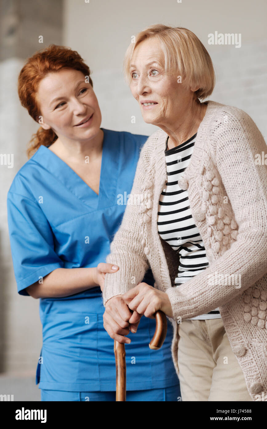 Prominent caring nurse helping her patient standing up Stock Photo - Alamy