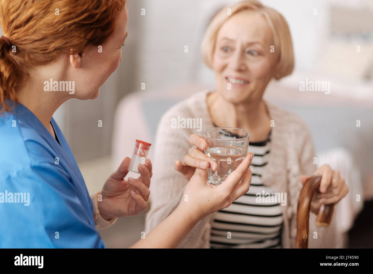 Kind trained nurse serving a glass of water Stock Photo - Alamy