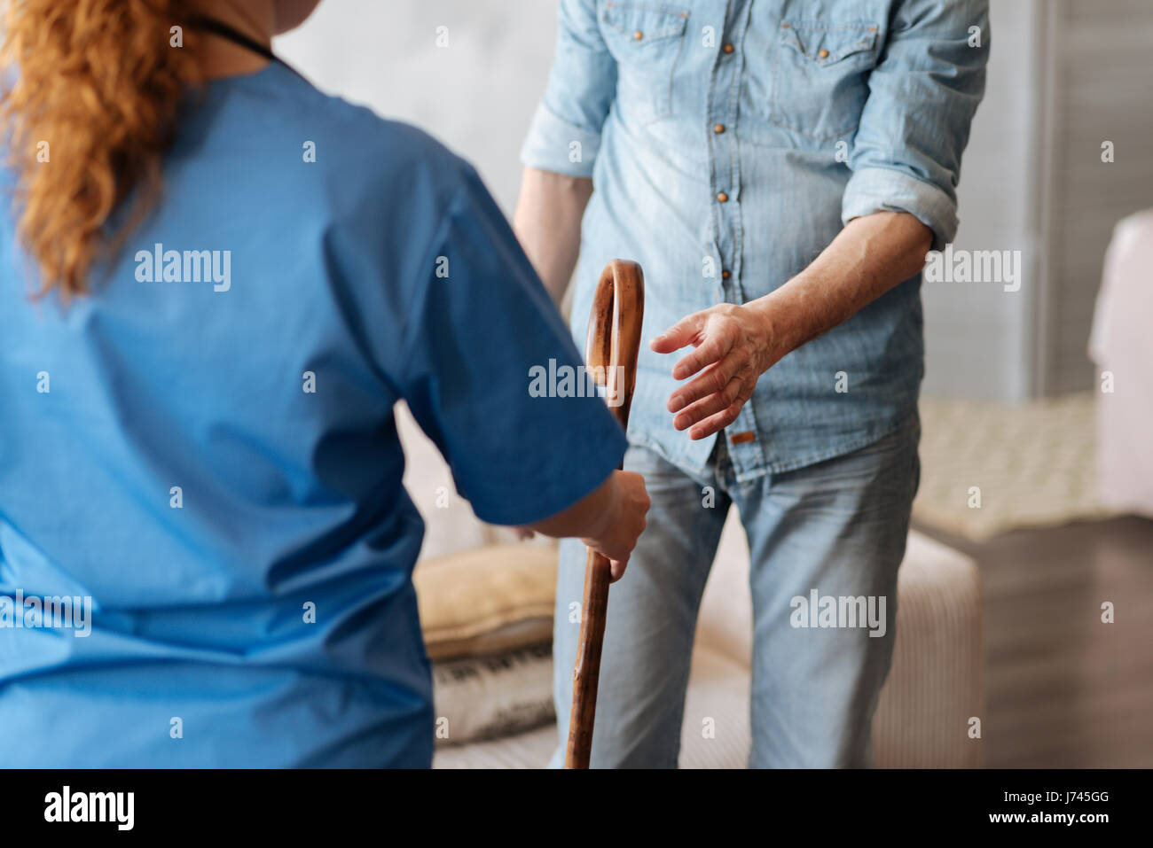 Committed kind medical worker giving her patient a cane Stock Photo - Alamy