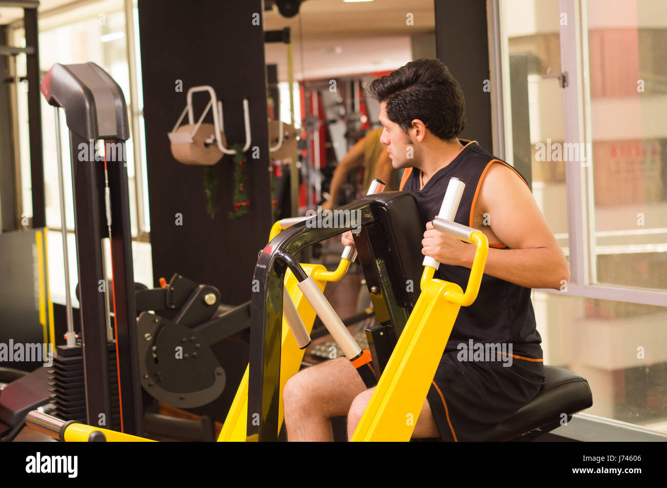 Handsome young man working on fitness machine at gym Stock Photo - Alamy