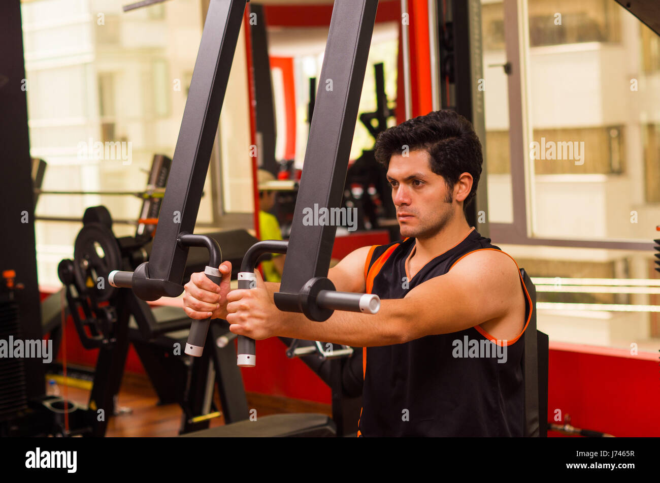 Young man in the gym and exercising Back on machine Stock Photo - Alamy