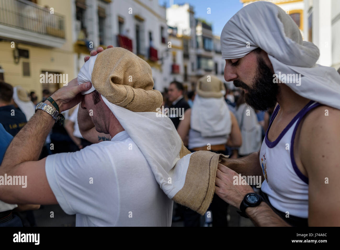 Costaleros putting into place the piece of sackcloth they wear on their ...