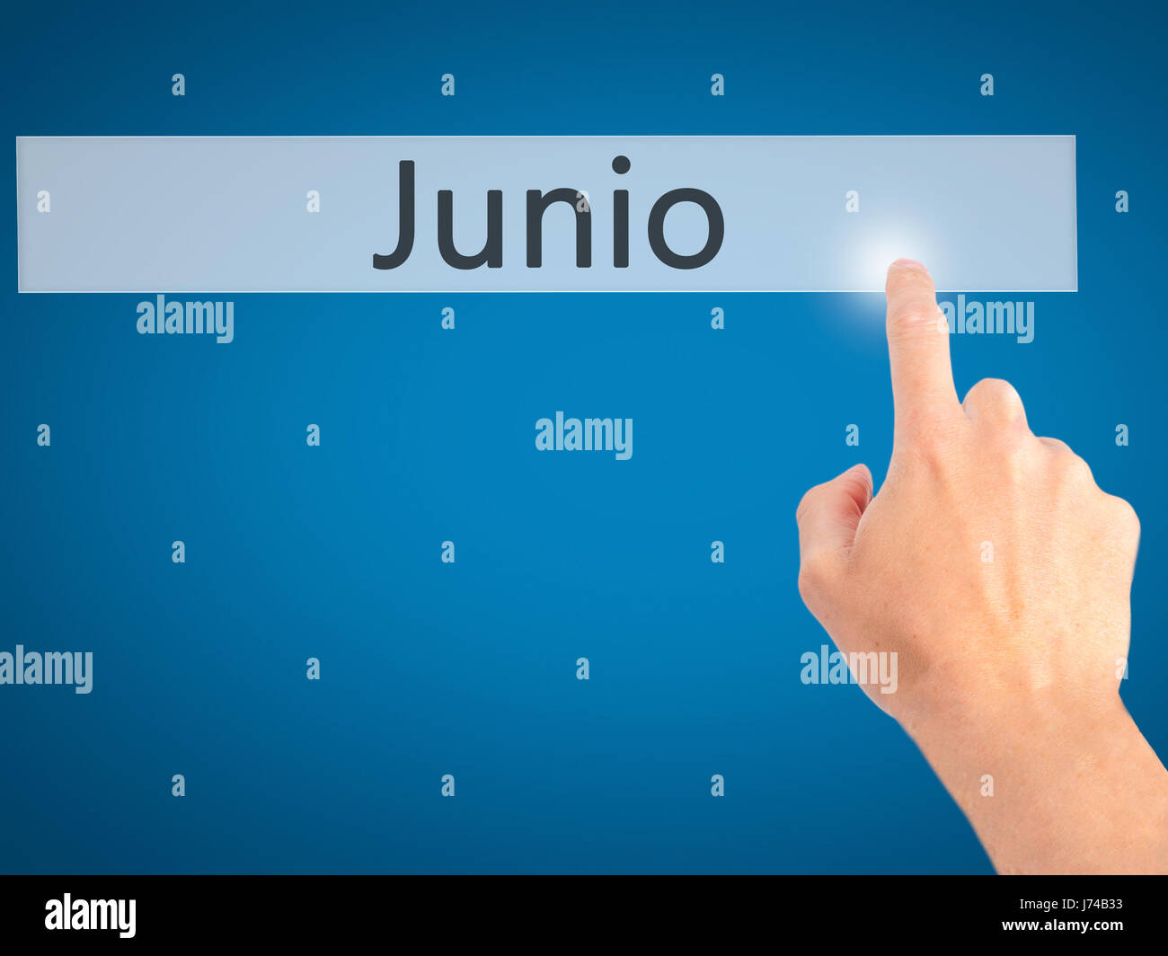 Junio (June in Spanish) - Hand pressing a button on blurred background ...