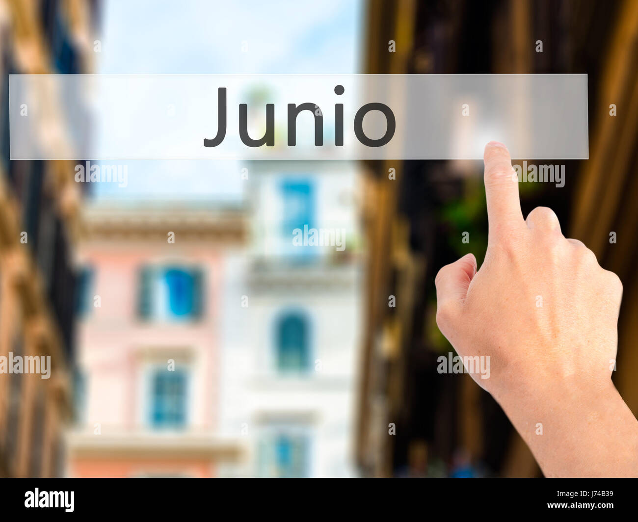 Junio (June in Spanish) - Hand pressing a button on blurred background ...