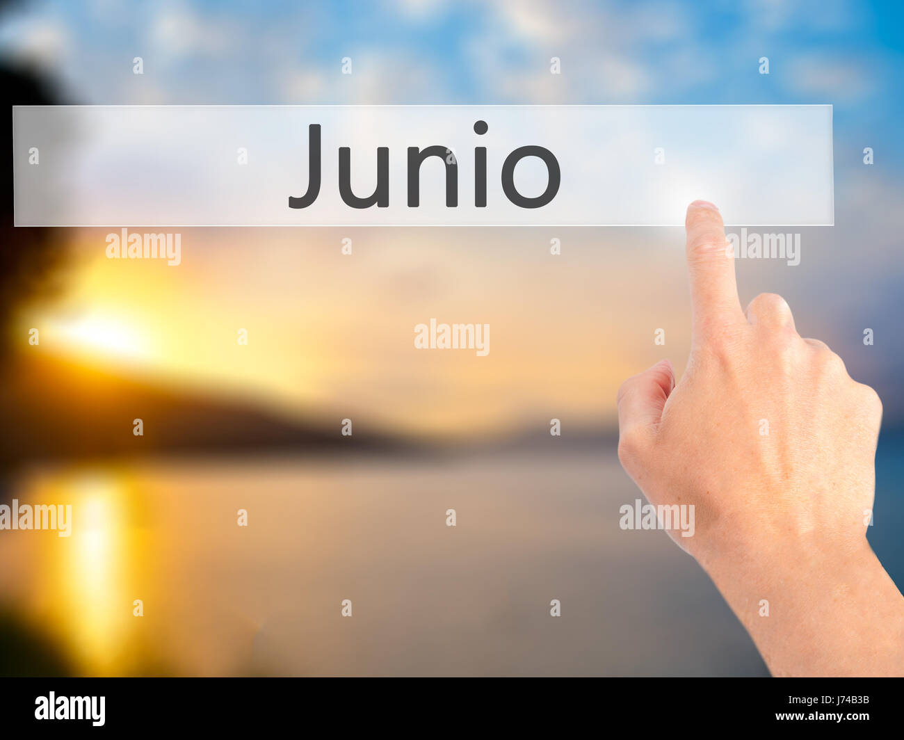 Junio (June in Spanish) - Hand pressing a button on blurred background ...