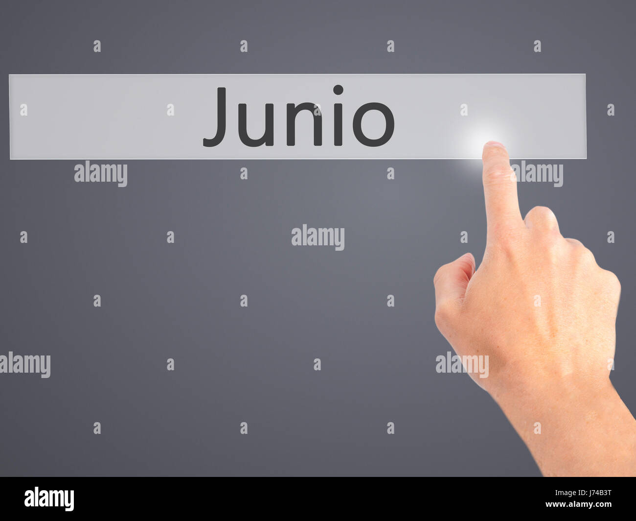 Junio (June in Spanish) - Hand pressing a button on blurred background ...
