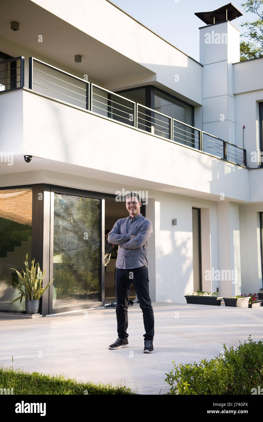 portrait of a young handsome successful man in front of his luxury home ...