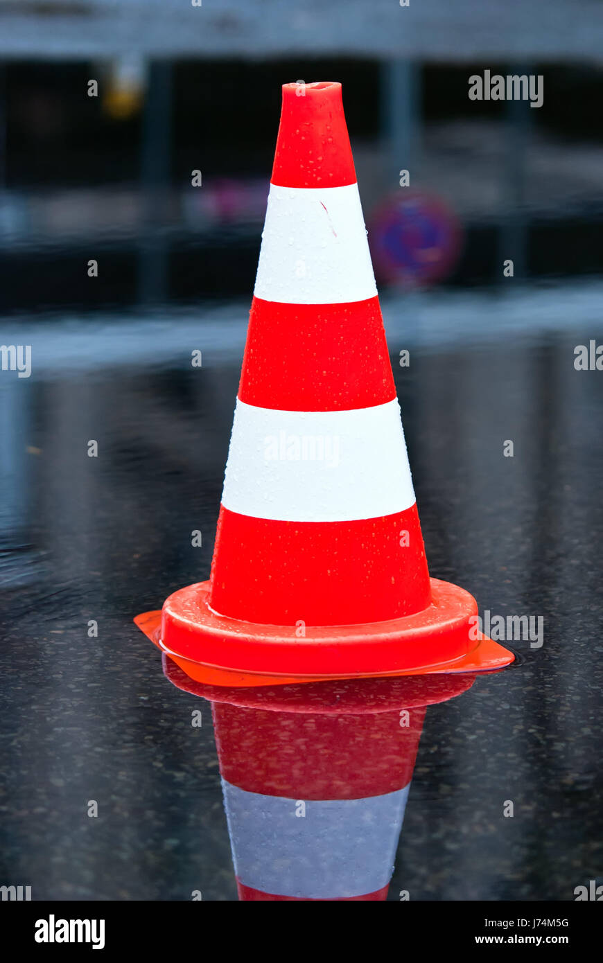 warning cone stands in puddle on the street v1 Stock Photo - Alamy