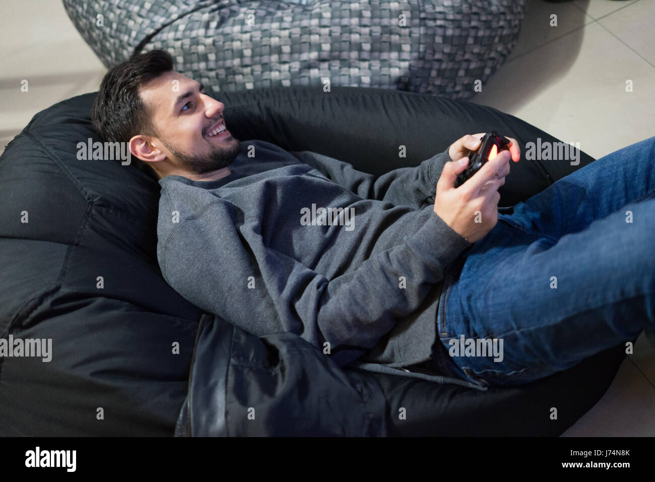 gamer playing video games with joystick sitting on Bean bag chair Stock ...