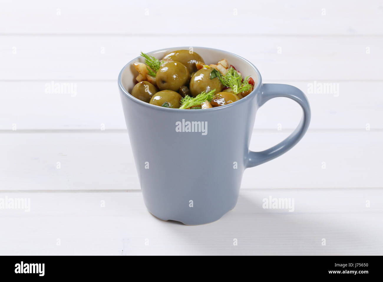 cup of marinated green olives on white wooden background Stock Photo ...